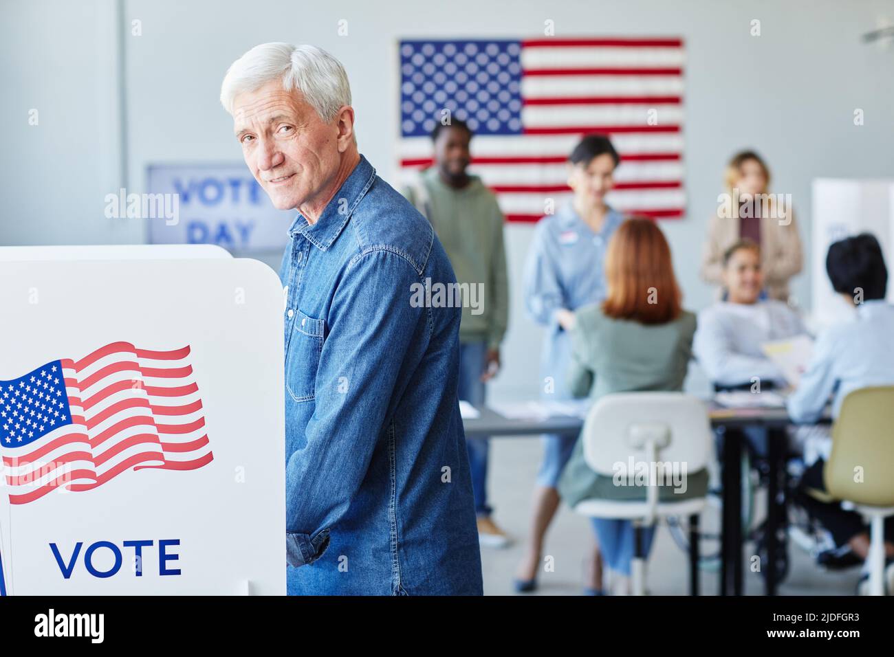 Side view portrait of smiling senior man voting in booth on election ...