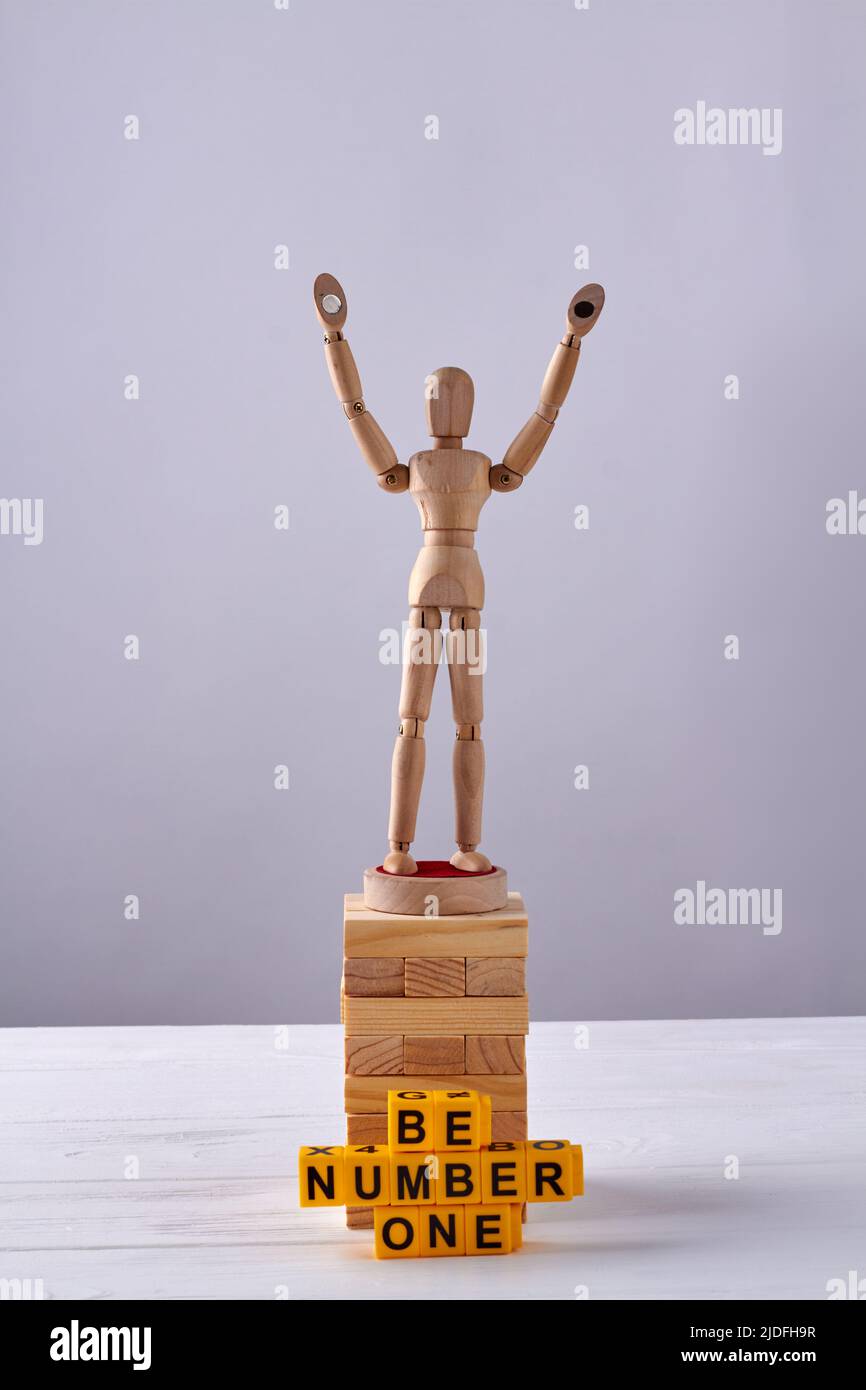 Vertical shot of wooden mannequin with raised arms. Yellow letters ...