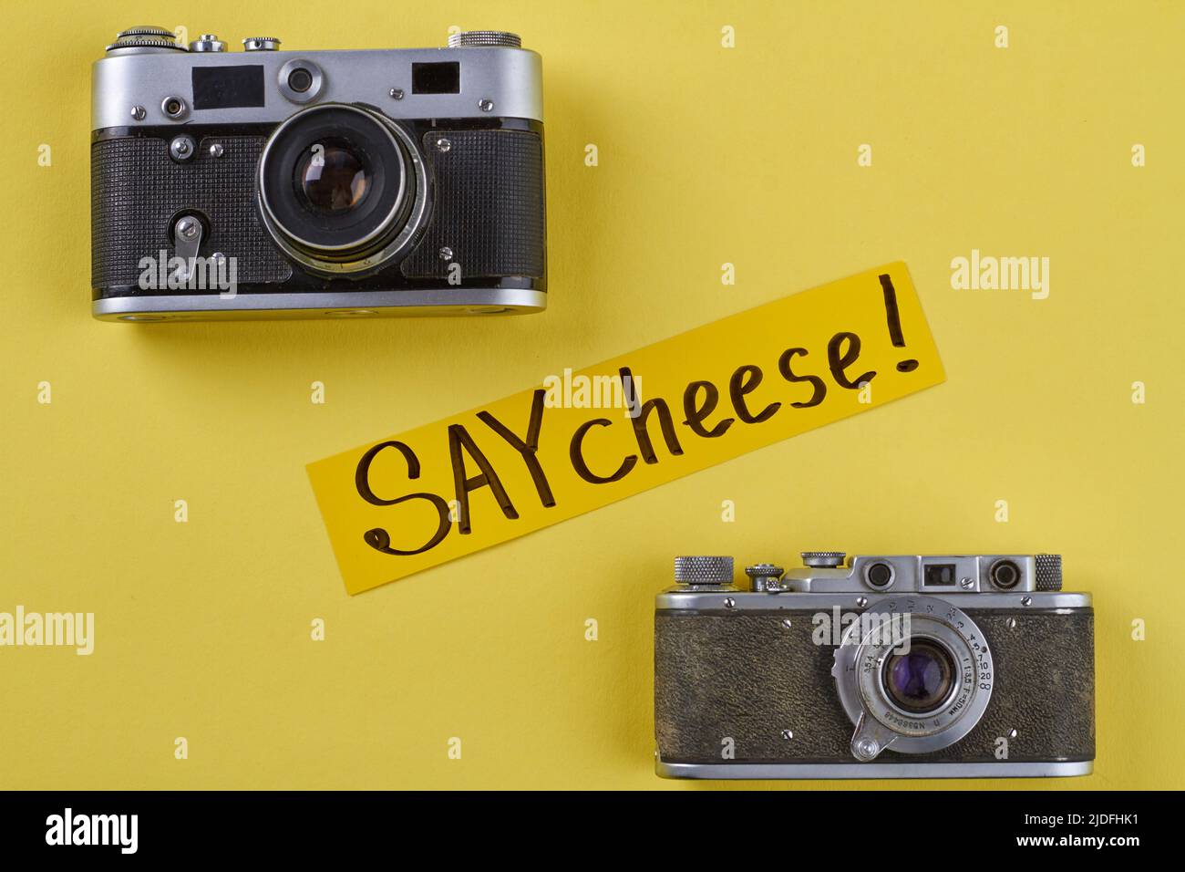 Two vintage photo cameras on yellow background. Say cheese handwriting ...