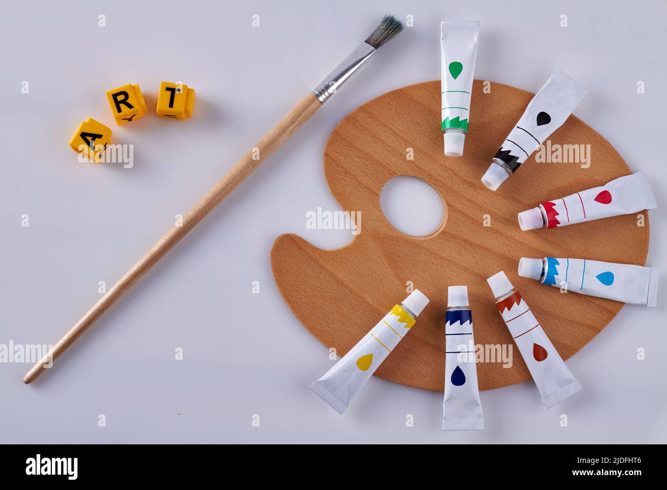 Top view paintbrush with wooden palette and oil tubes. Yellow letter ...