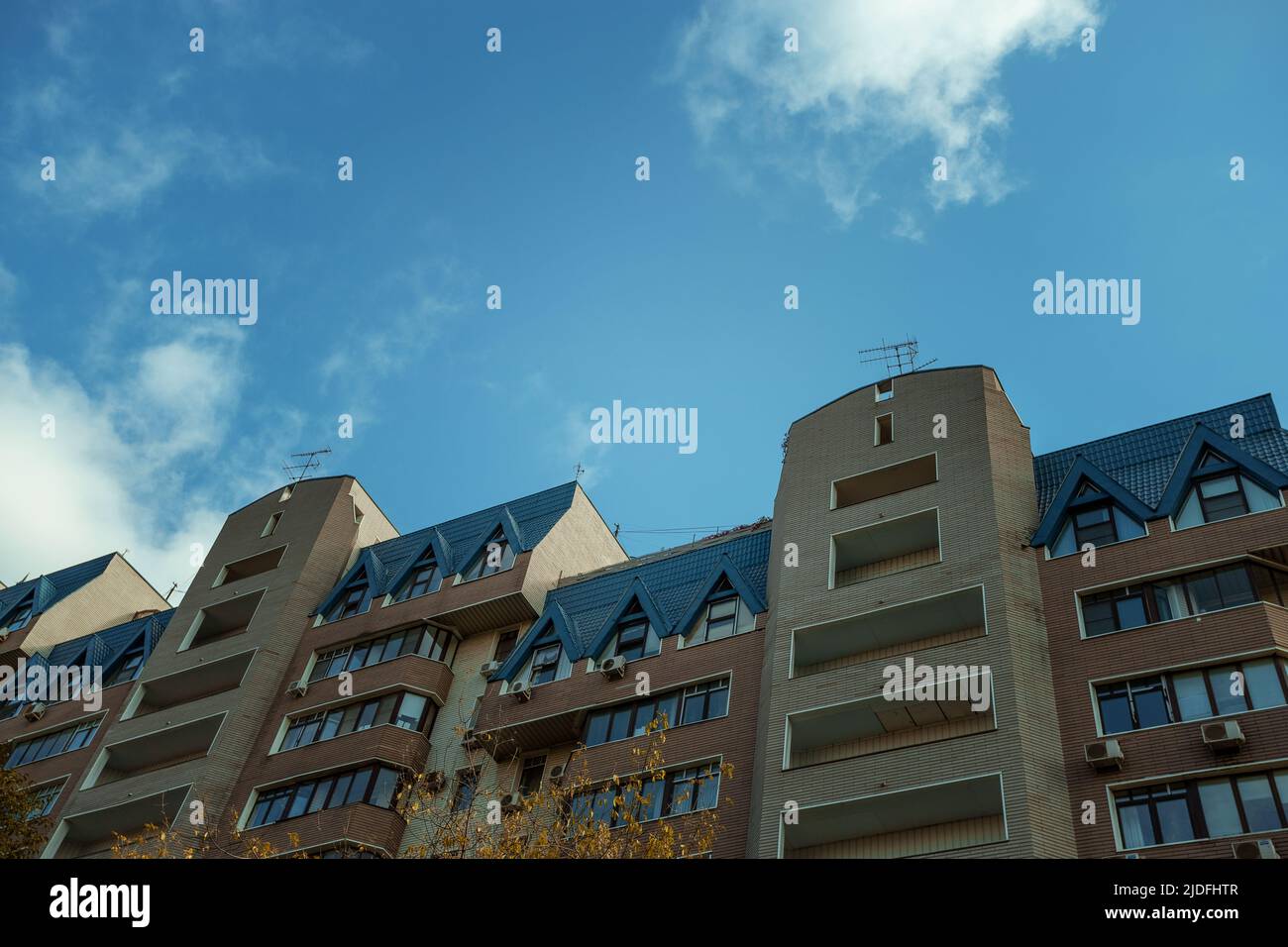 Facade of a high-rise apartment building against a blue sky with fluffy ...