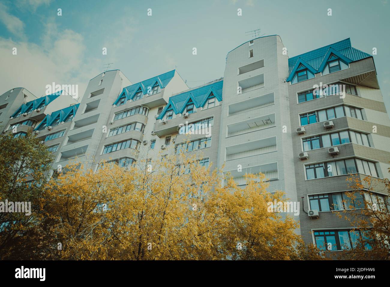Facade of a high-rise apartment building against a blue sky with fluffy ...