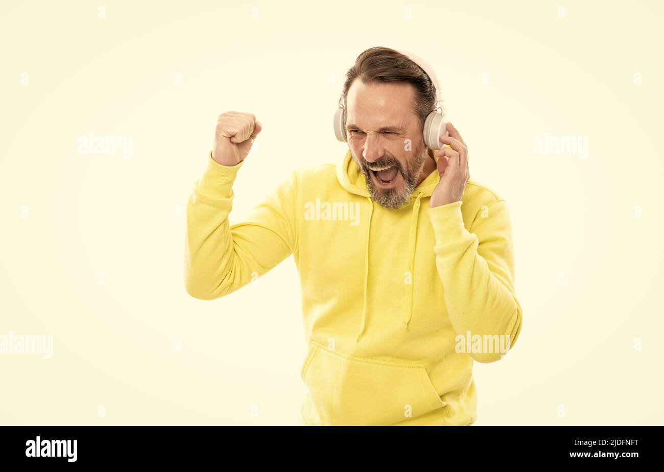 cheerful mature man in hoody listen music or audio book in headphones ...