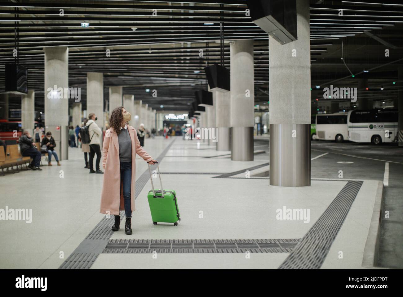 Woman traveler with ffp2 respirator going trough bus station with ...