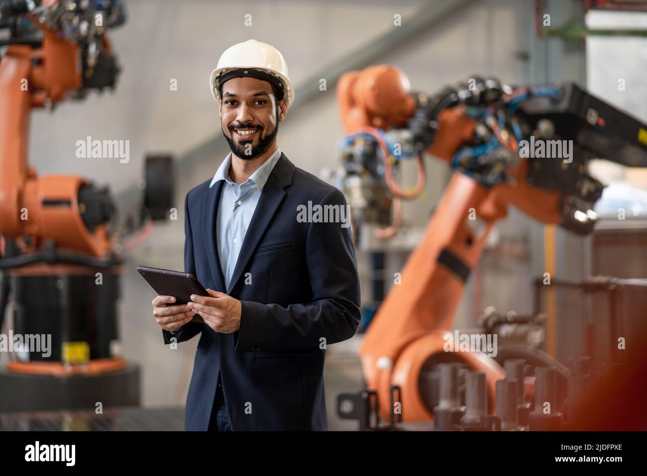 Automation engineer uses tablet for programming robotic arm in factory ...