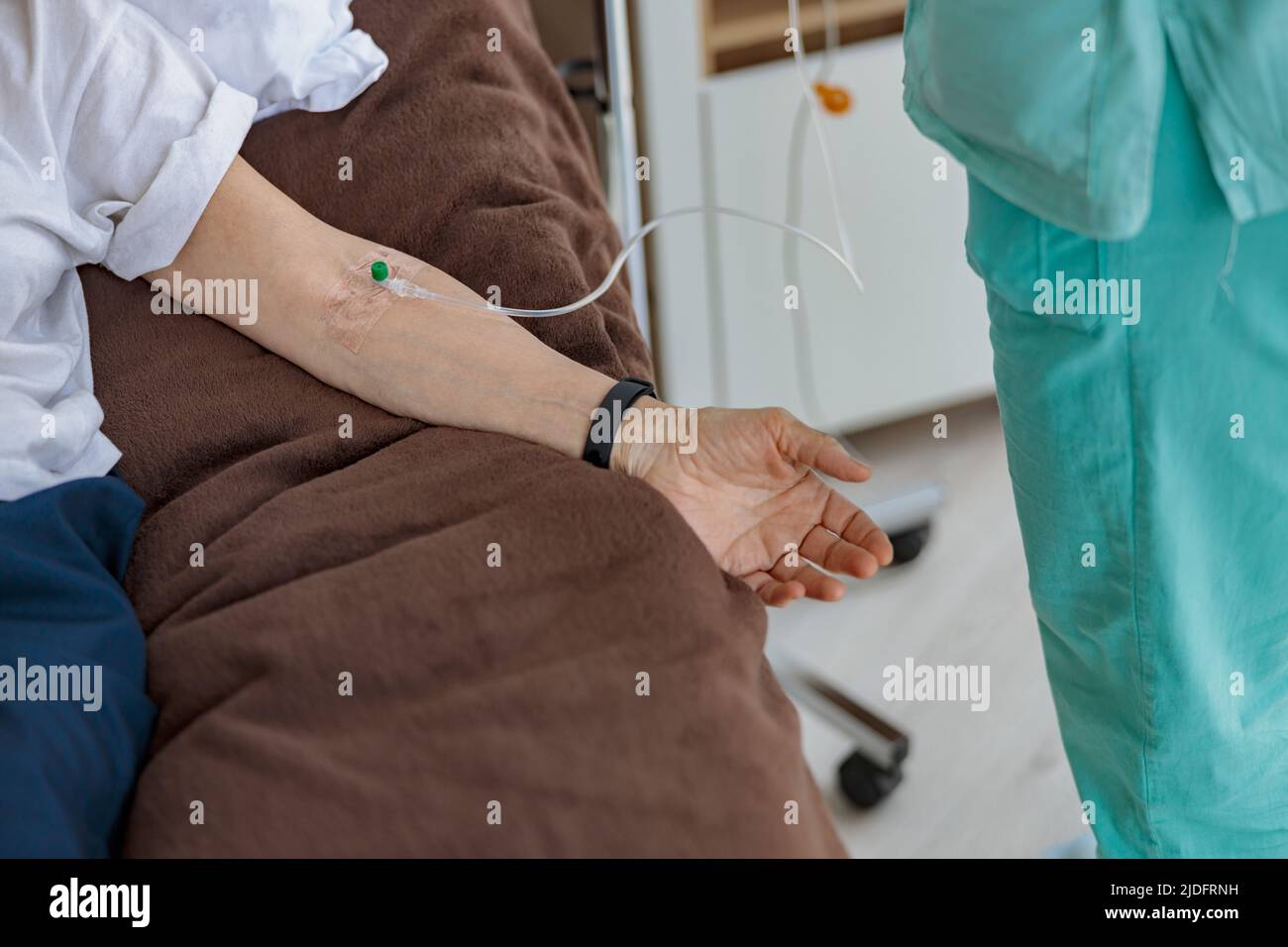 Nurse putting a drip in the arm of her patient in modern medical clinic ...