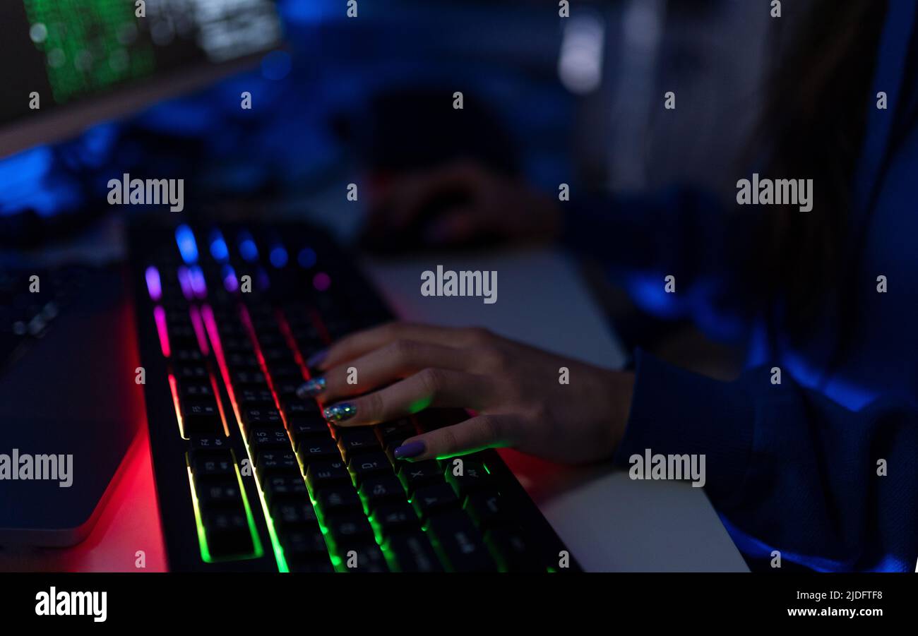 Close-up of woman hacker hands at keyboard computer in the dark room at ...
