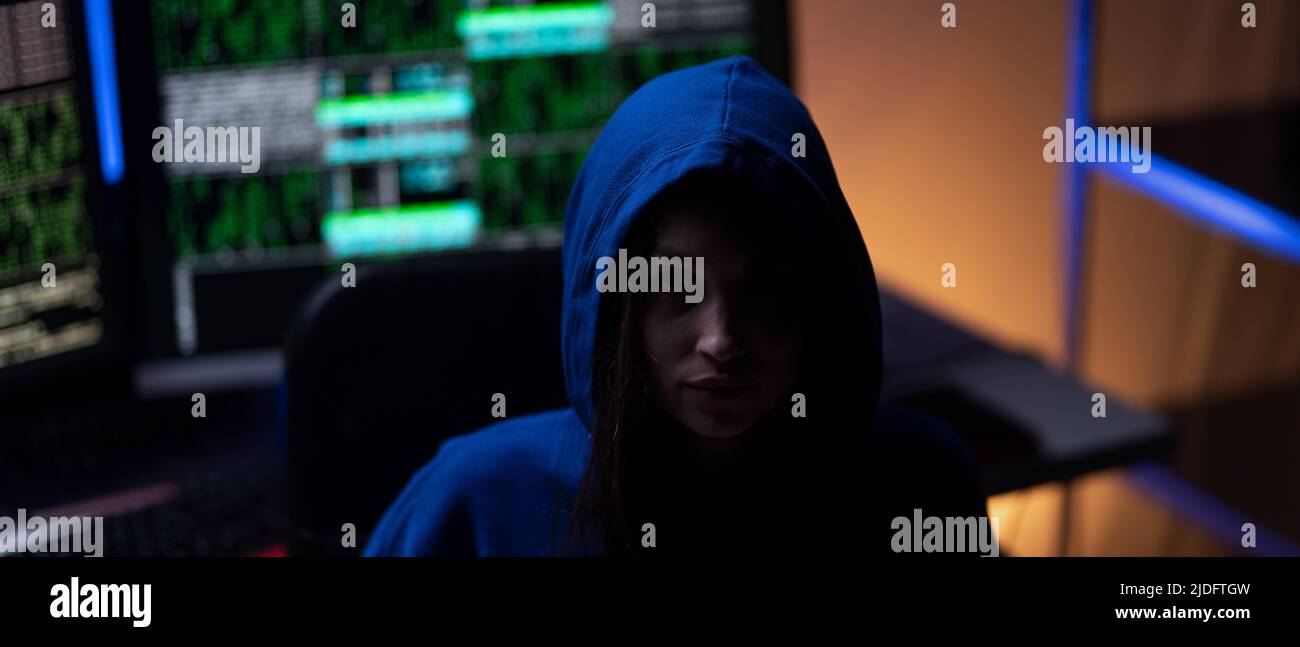 Hooded anonymous hacker by computer in the dark room at night, cyberwar ...