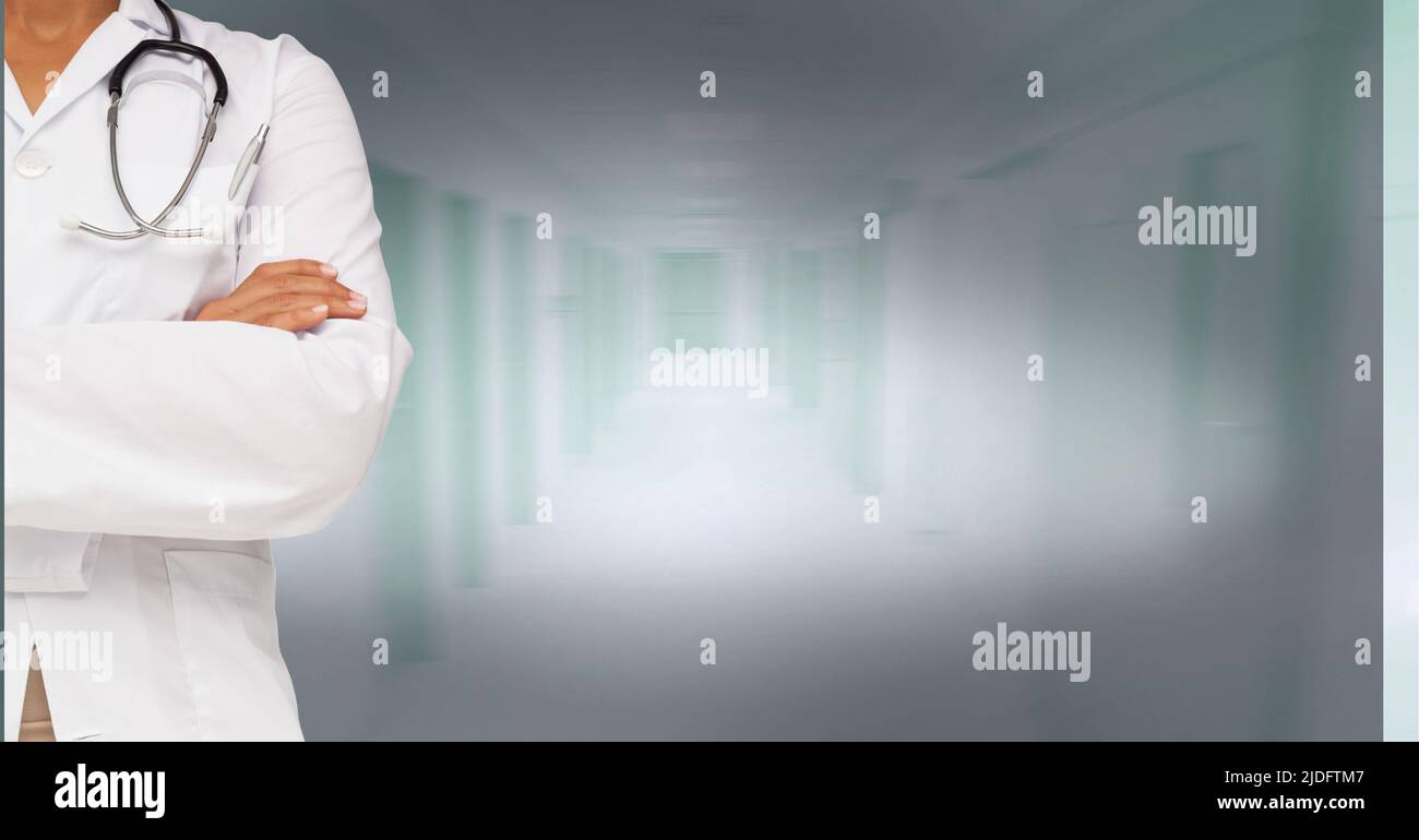 Mid section of mixed-race female doctor with arms crossed against ...