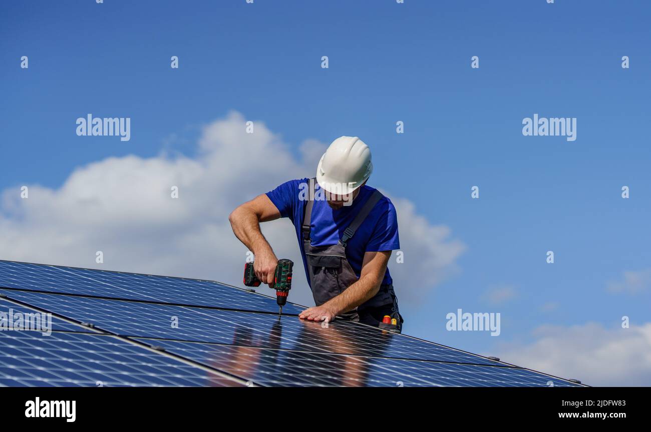 Man worker installing solar photovoltaic panels on roof, alternative ...