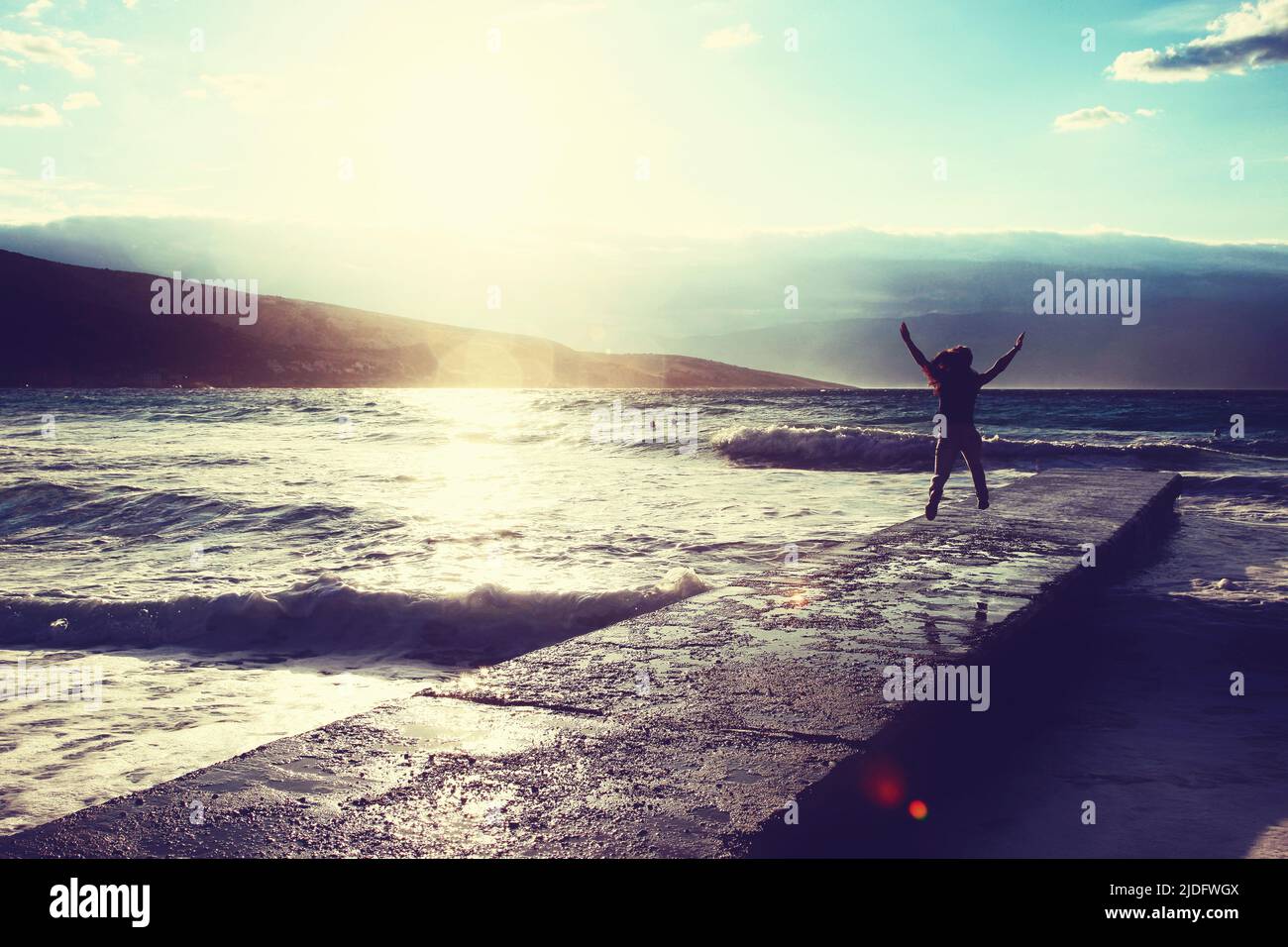 Feeling of freedom concept. Woman jump on pier facing to the sea with ...