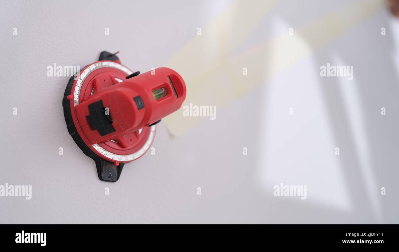 Close-up of red construction laser level fixed on white wall ...