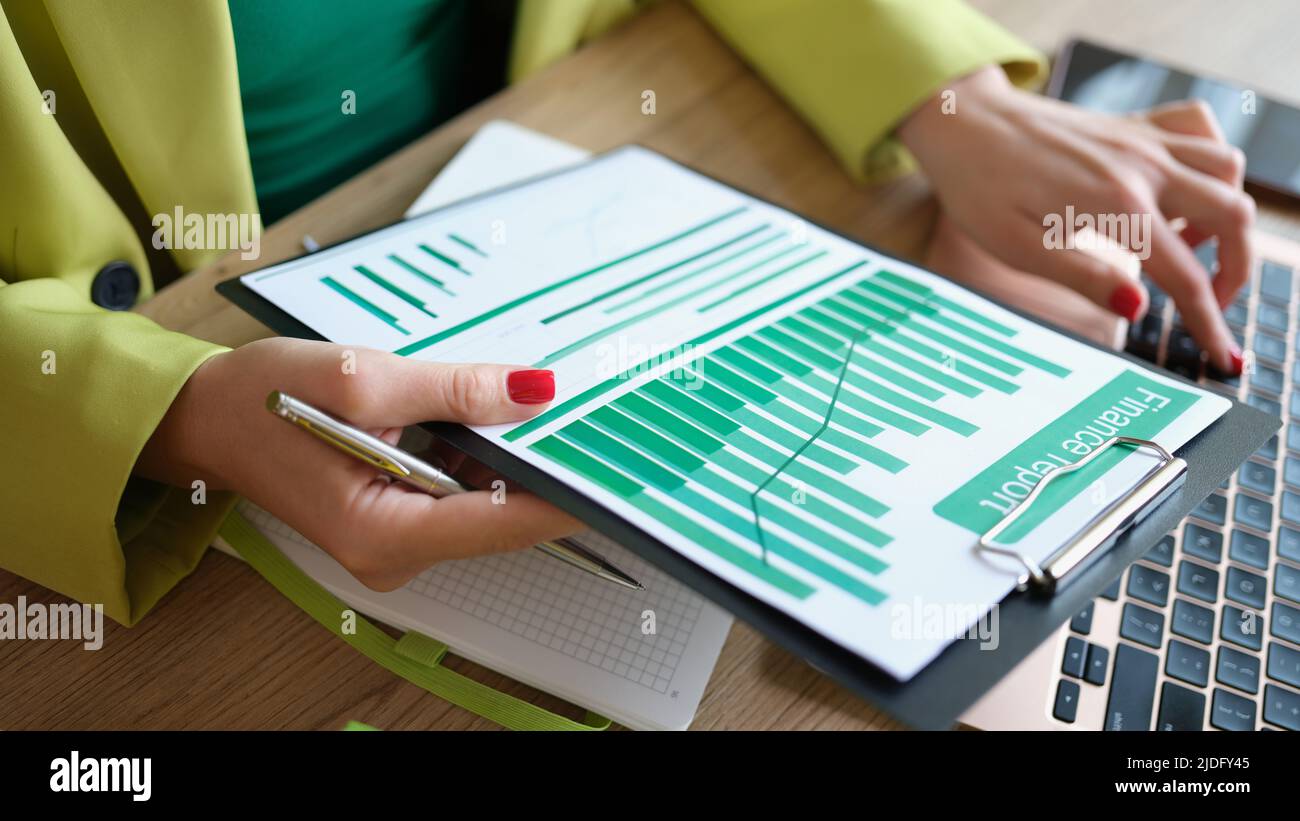 Close-up of female accountant using laptop for typing financial report ...