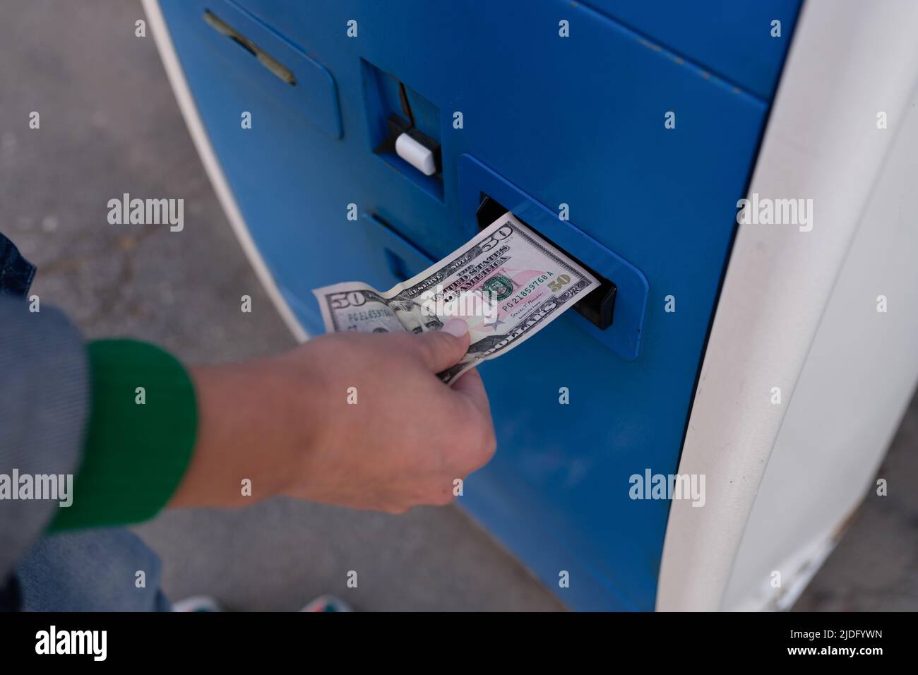 Woman paying for parking using cash at teller machine Stock Photo - Alamy