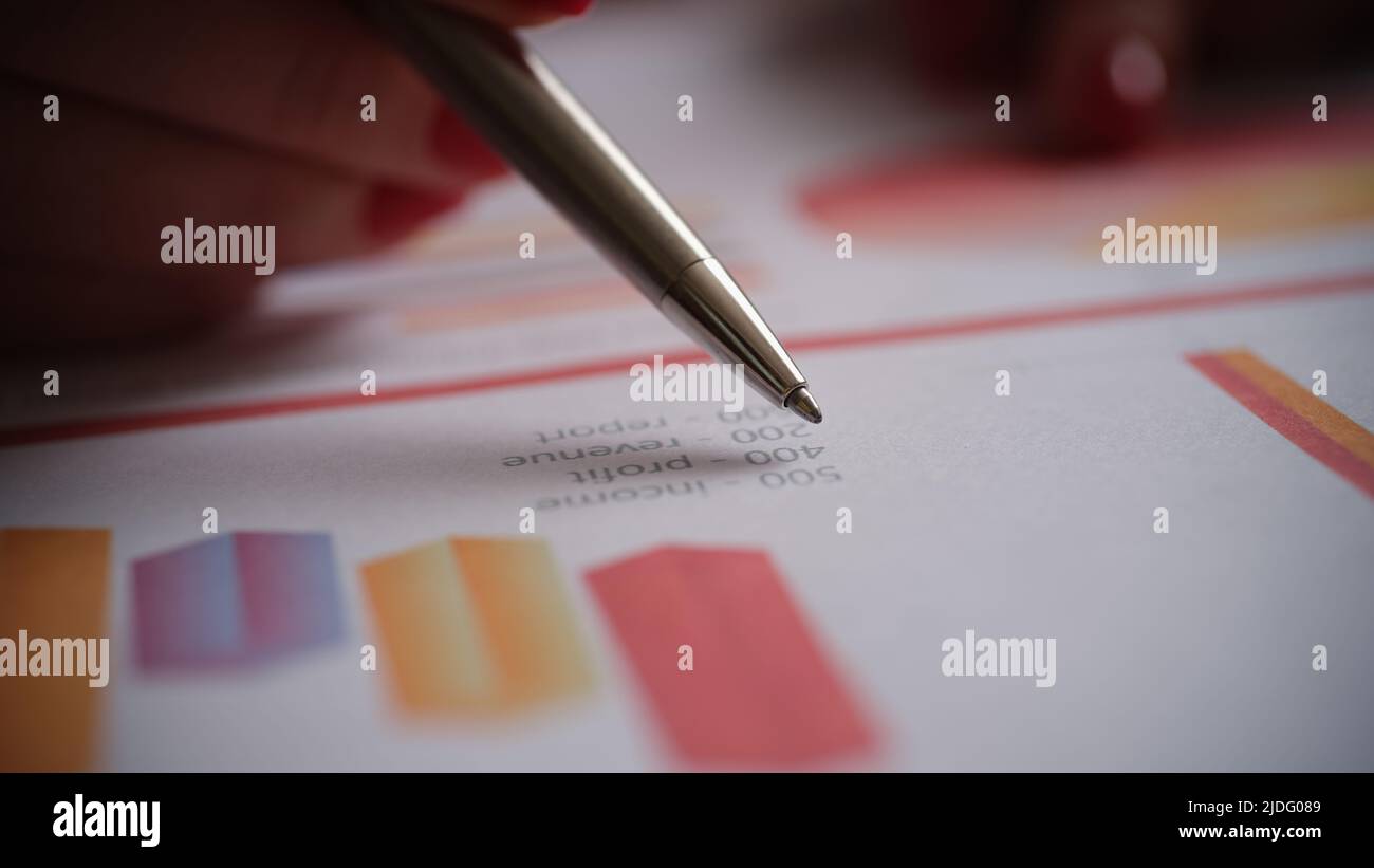 Woman hand pointing with pen on report with colourful diagrams Stock ...