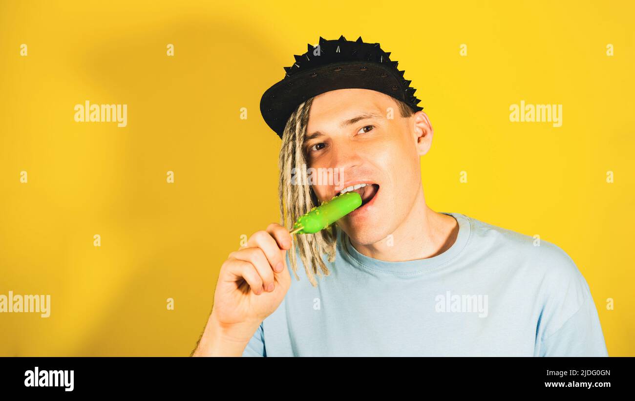 Young handsome man in black cap biting ice cream, smiling, looking at ...