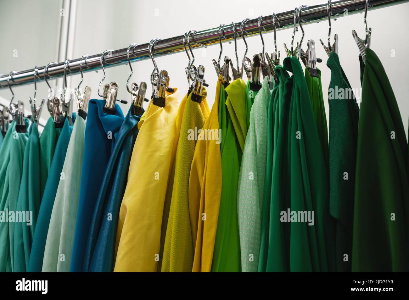 Samples of green yellow and blue fabrics hang on rack bar Stock Photo ...