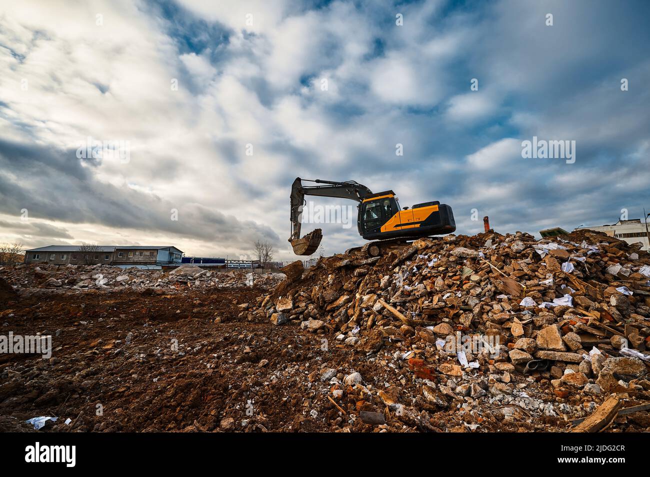 Excavator pours soil on pile of garbage at demolition site Stock Photo ...