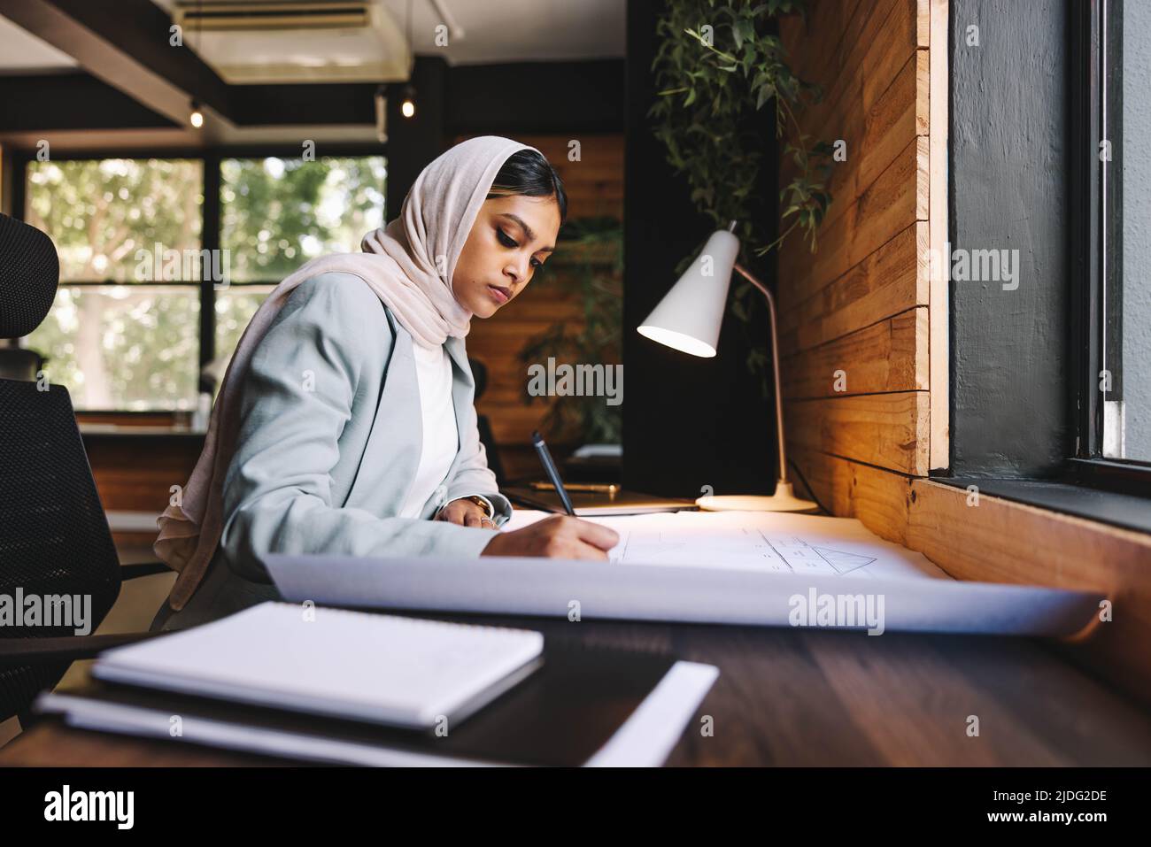 Creative Muslim designer working with architectural drawings in a ...