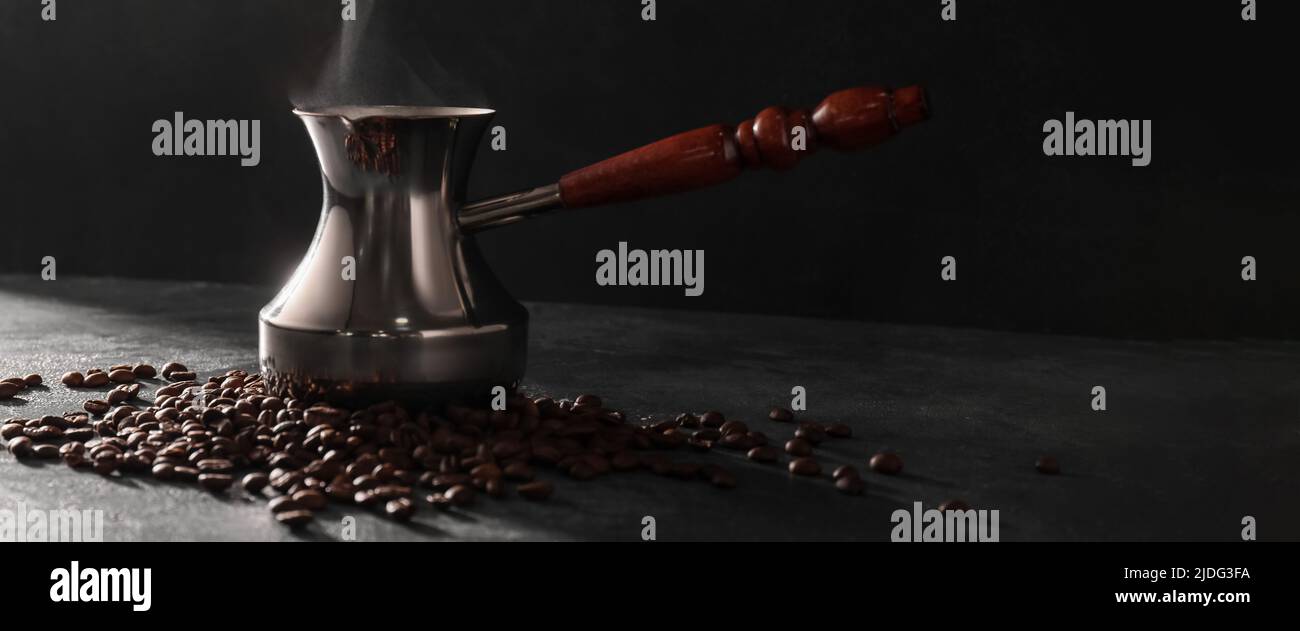 Jezve with hot coffee and beans on dark background Stock Photo - Alamy