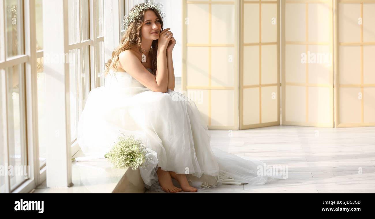 Beautiful bride with bouquet of flowers sitting on window sill. Banner ...