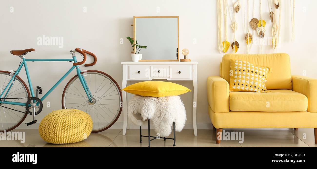 Interior of light room with yellow armchair, dressing table and bicycle ...