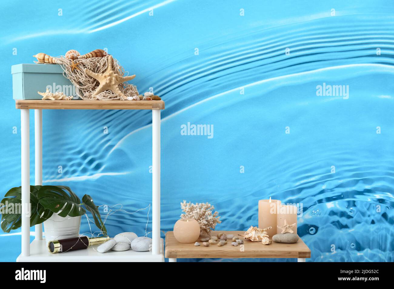 Shelves with burning candles and sea shells near wall with print of ...