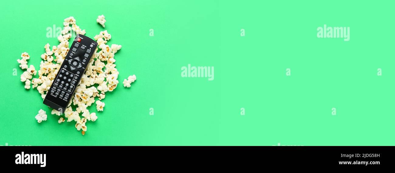 Modern TV remote control with popcorn on green background with space ...