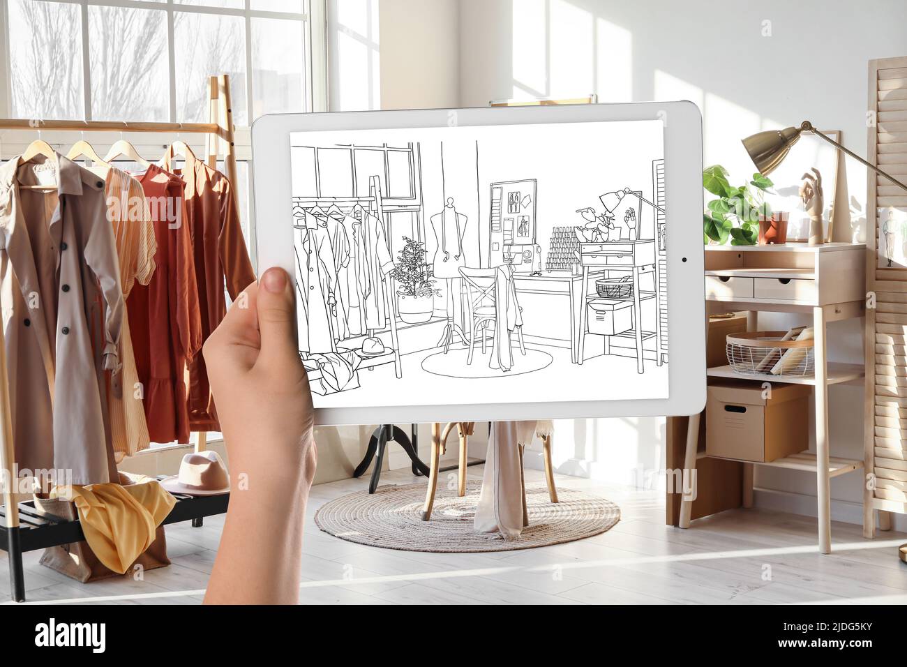Designer holding tablet computer with drawing of new atelier interior ...