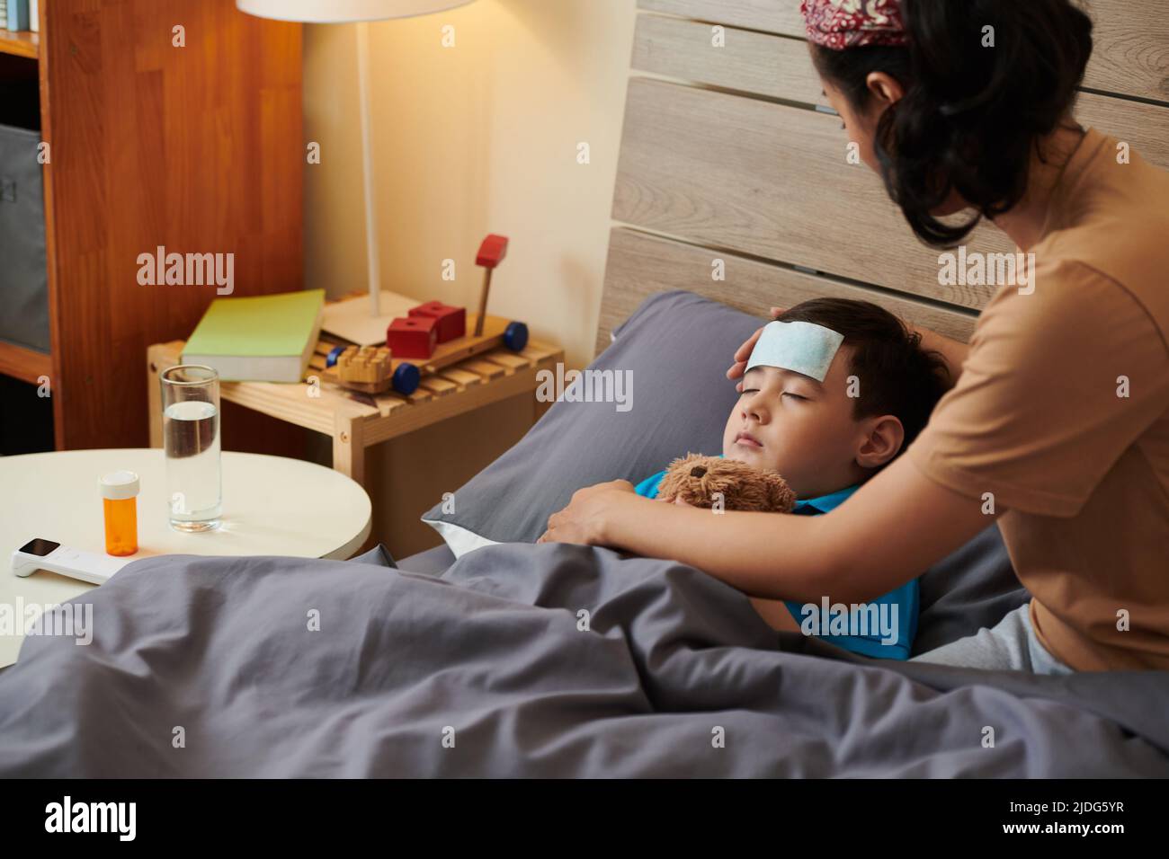 Mother caring about son having fever, she is hugging him and sticking ...