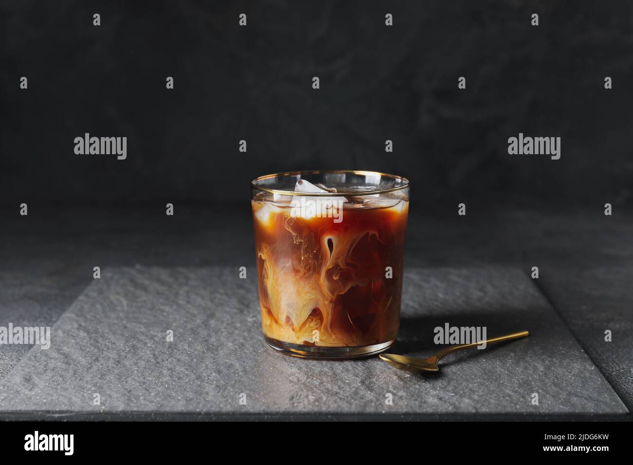 Glass of cold brew coffee with milk and spoon on dark background Stock ...