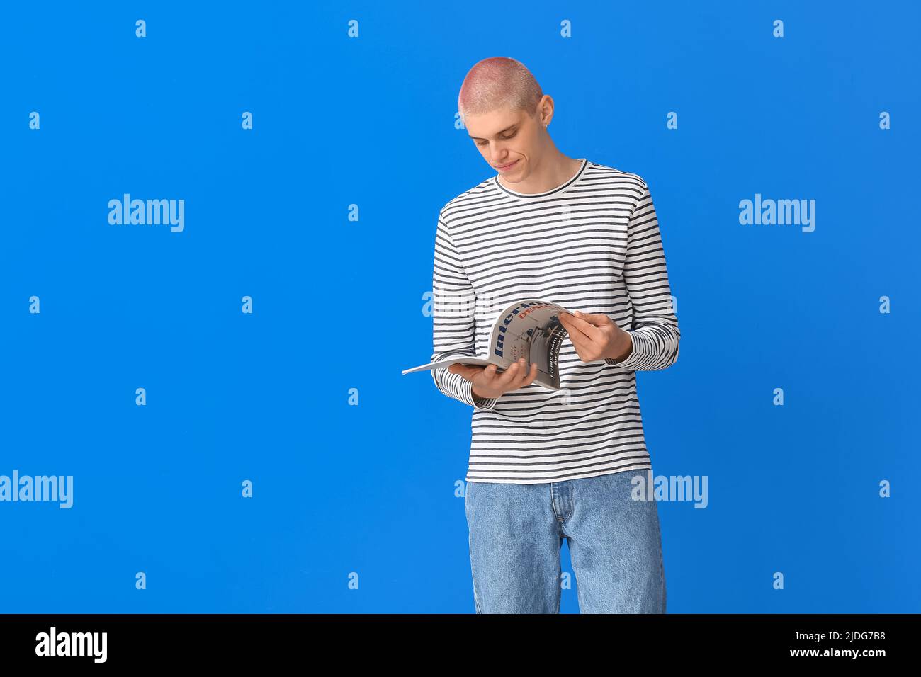 Young guy reading magazine on blue background Stock Photo - Alamy