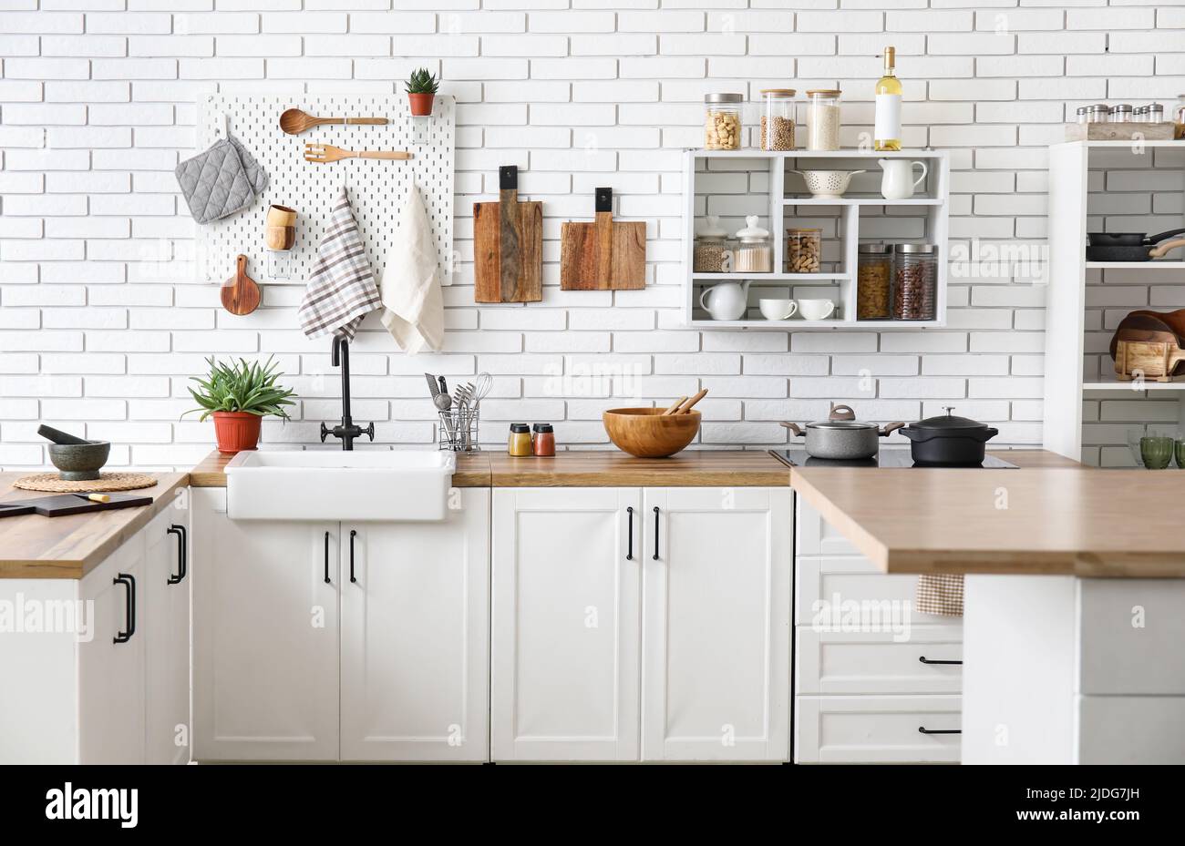 Kitchen counters with utensils and shelf unit on white brick wall Stock ...