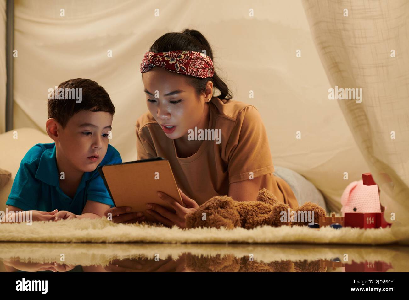 Little boy listening to mother reading e-book with stories for kids ...
