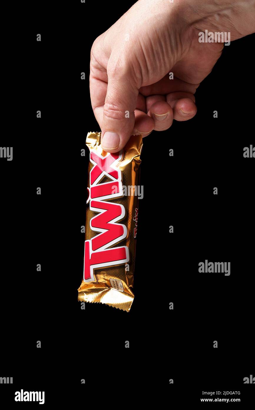 Chocolate bar Twix in a man's hand close-up, black background, vertical ...