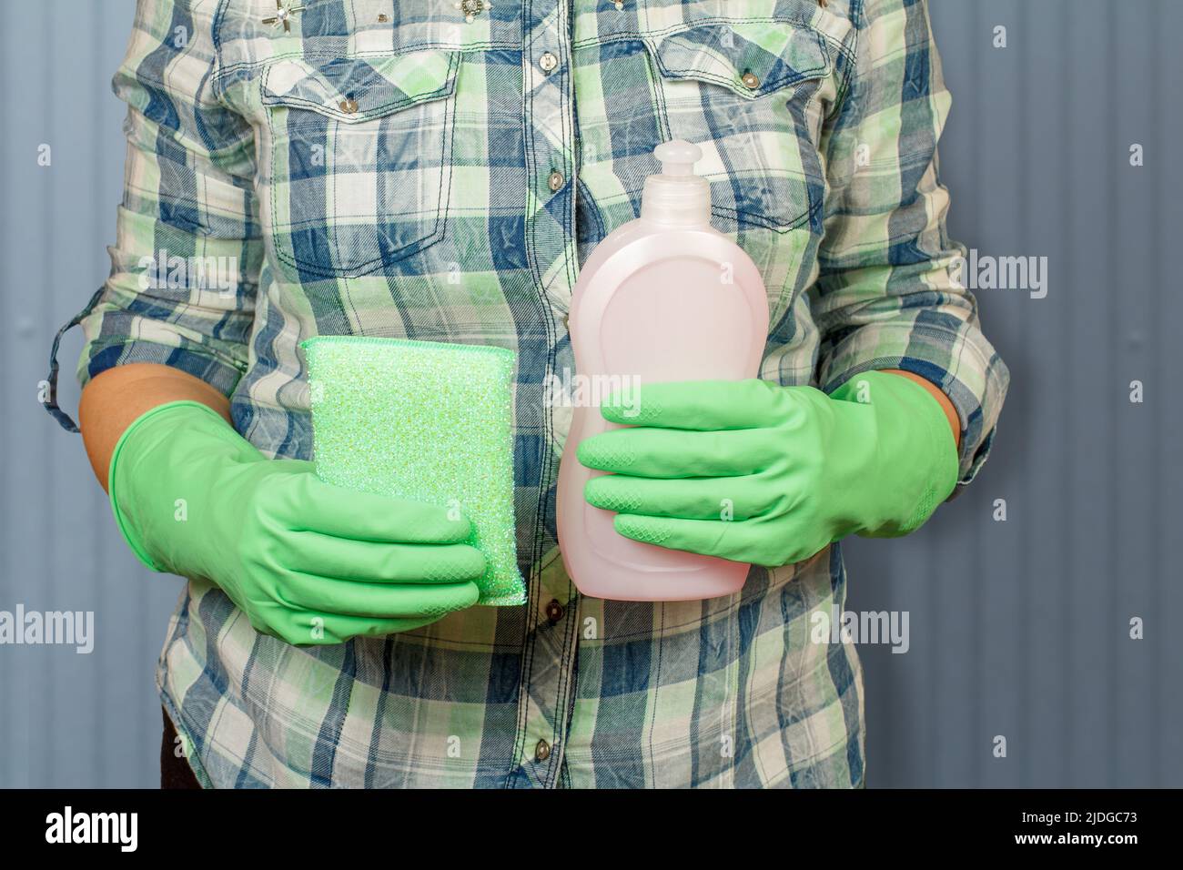 Women's hands in rubber gloves holding the plastic bottle of washing ...