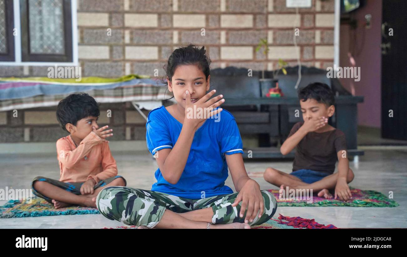Three Indian little kids doing meditate yoga asana on roll mat at home ...