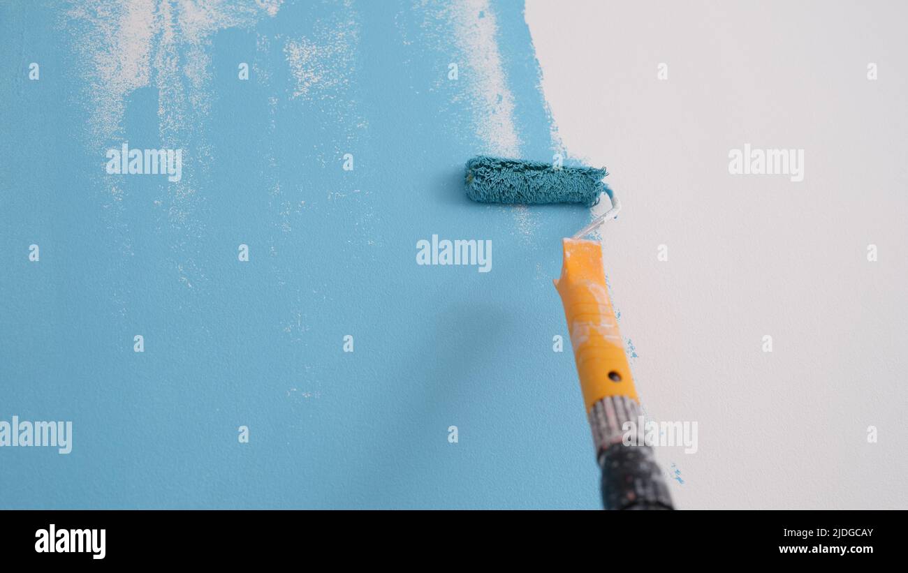 Professional decorator painting wall in blue color Stock Photo - Alamy