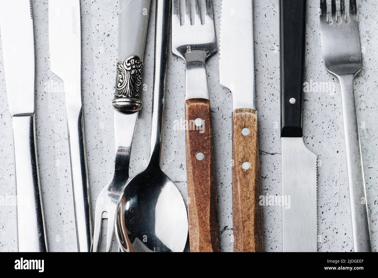 Close up of cutlery on a table surface. Knifes, forks and spoon made of ...