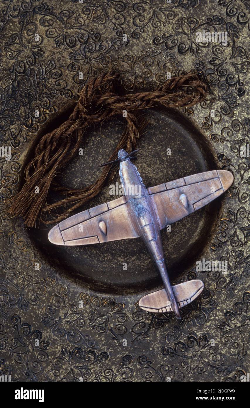 Brass model of small airplane lying with short length of loosely ...
