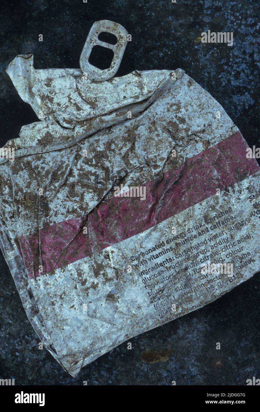 Squashed and split aluminium drinks can with covering of dirt lying on ...