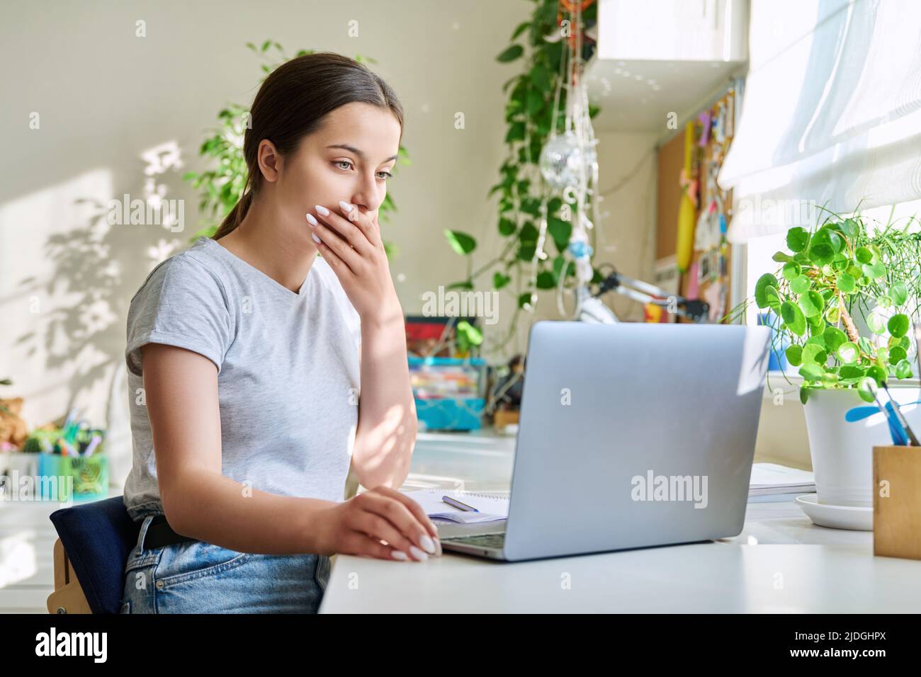 Teenage girl studying at home at the table using a laptop Stock Photo ...