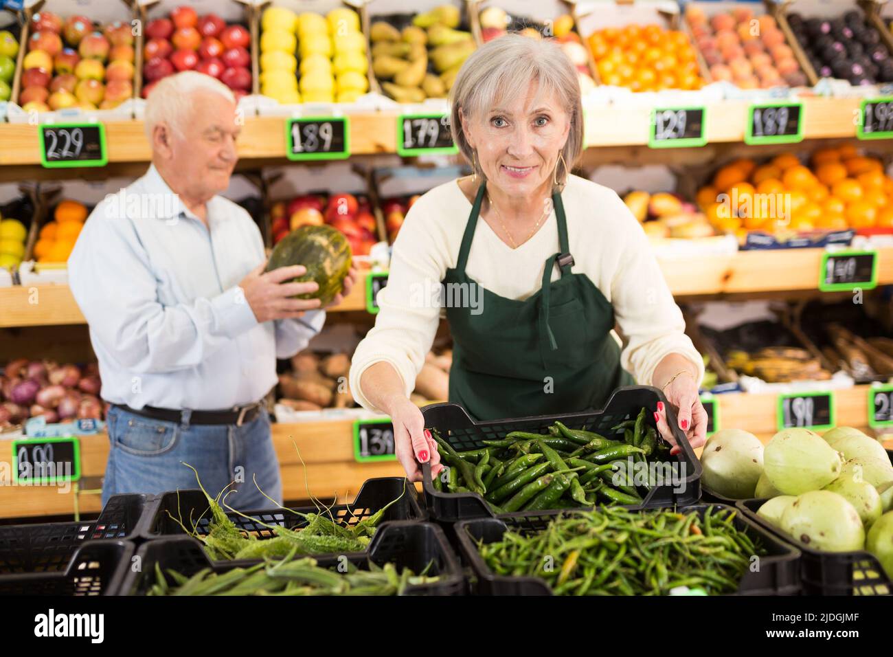 Female supermarket worker carries box of green chili peppers Stock ...
