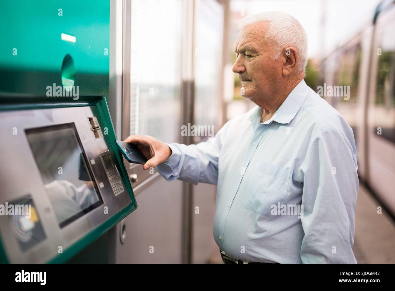 Old man using cash machine with smartphone Stock Photo - Alamy