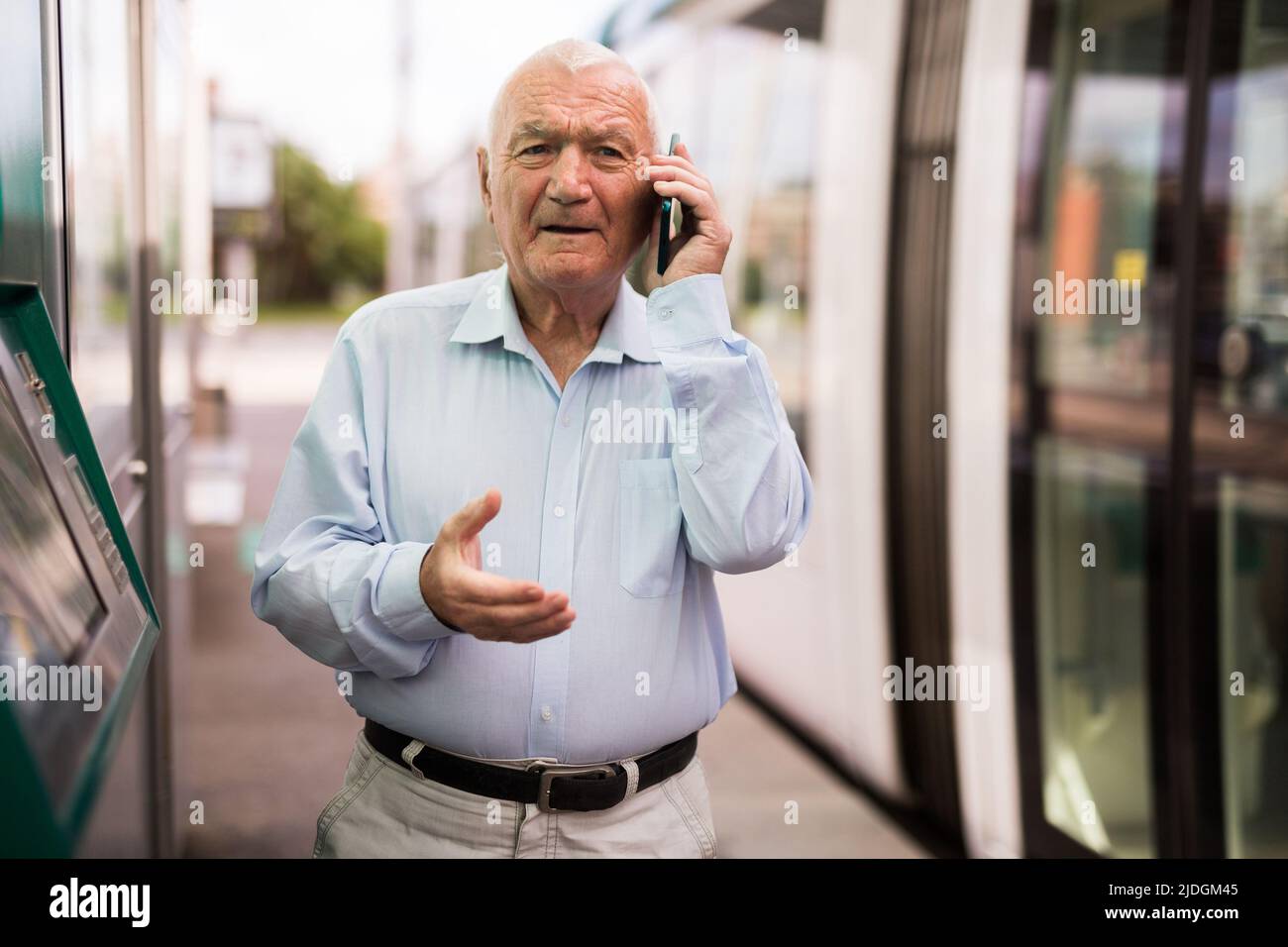 Old man talking on phone in tram station Stock Photo - Alamy
