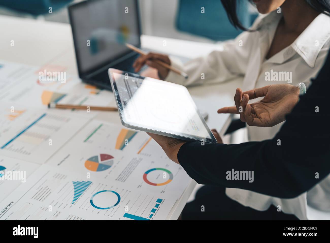 Business partnership coworkers using digital tablet to chart company ...