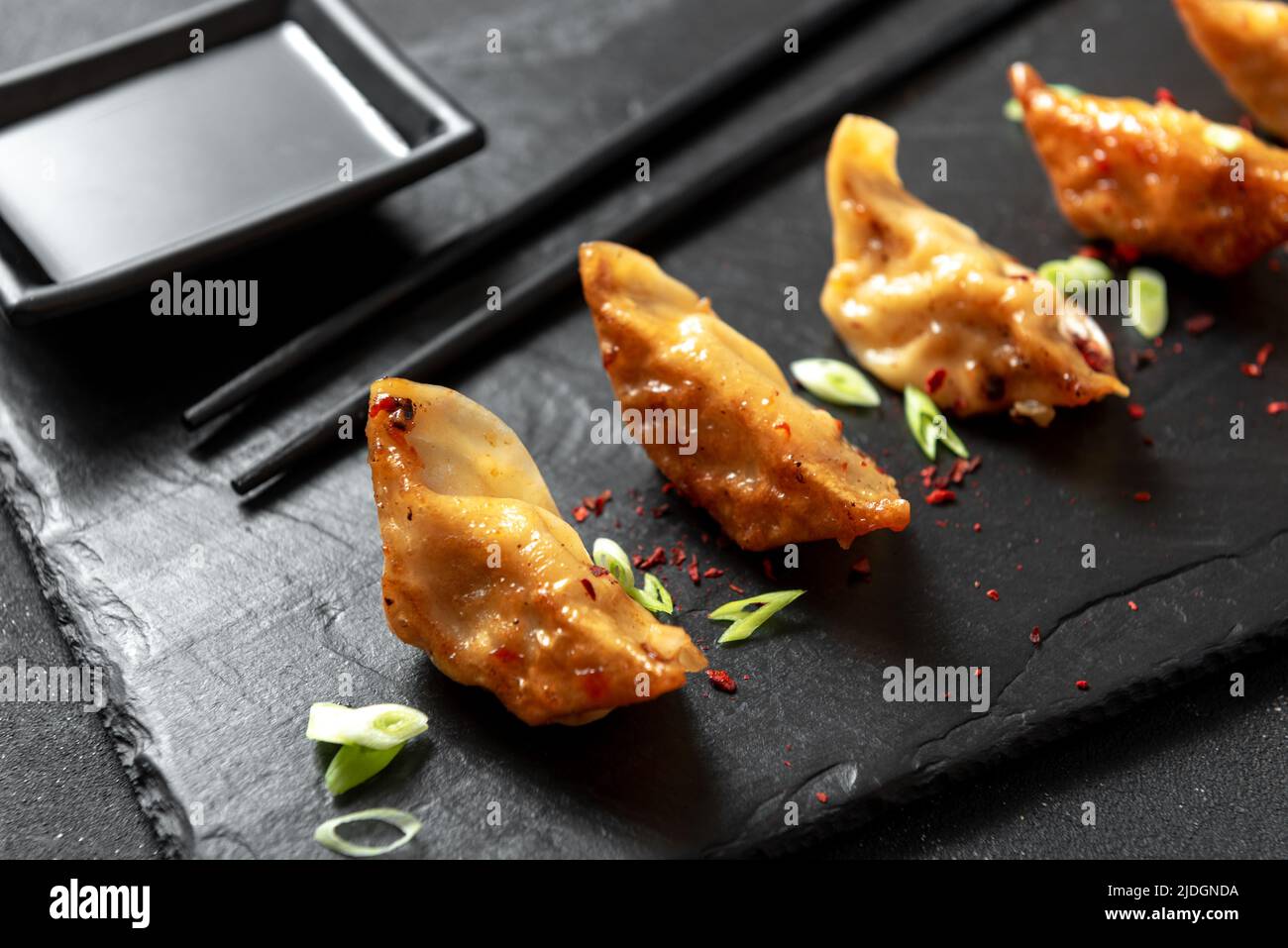 Japanese Fried Dumplings with onions on a black background. Gyoza is a ...