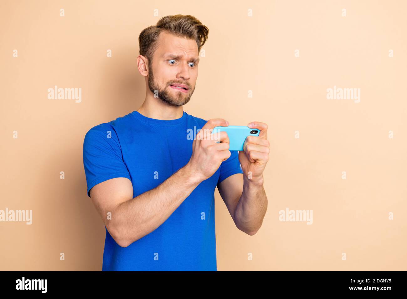 Photo of young man moody anxious play game mobile bite lips failure ...