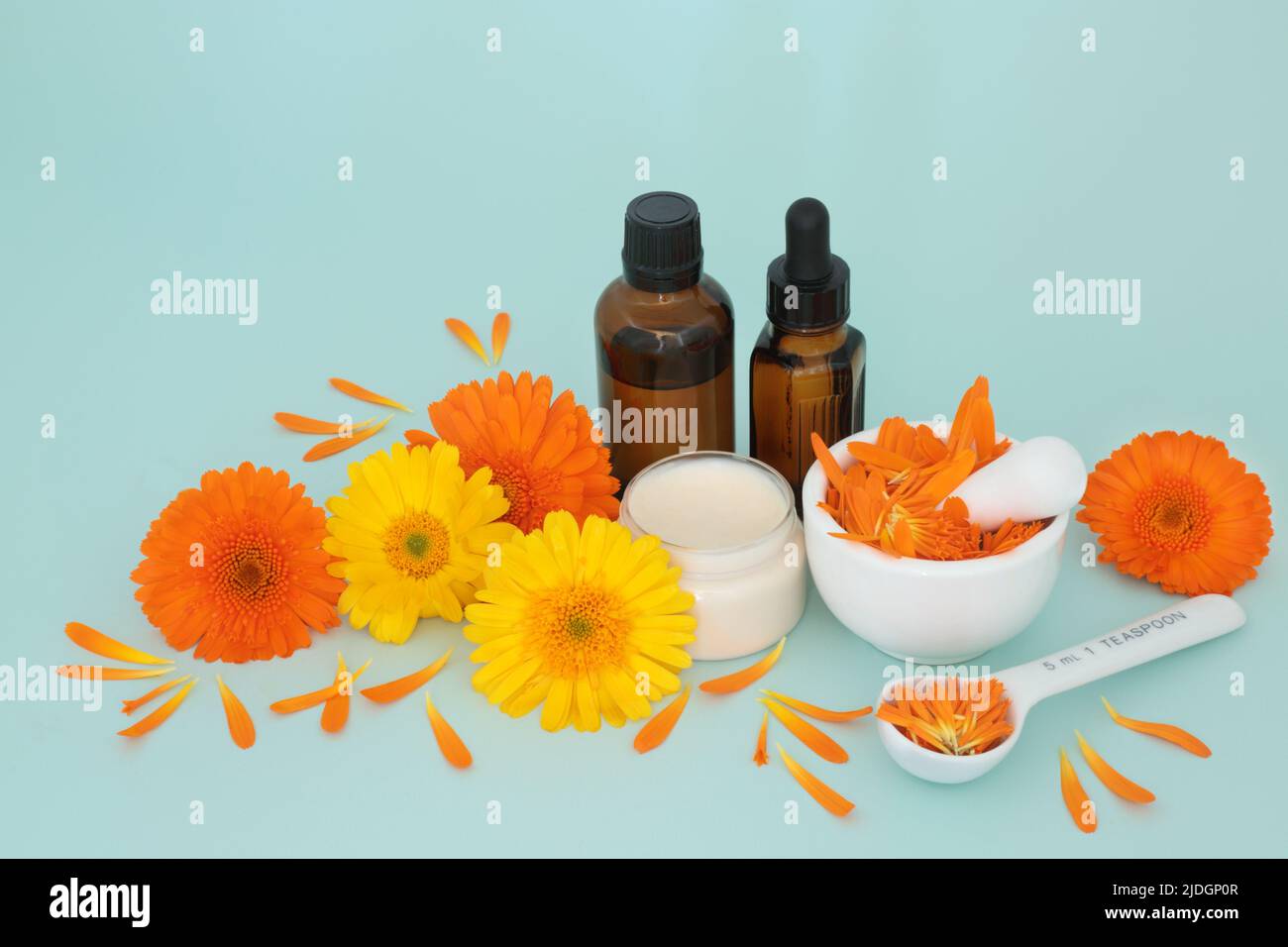 Calendula flowers for skincare with ointment, essential oil bottles and ...