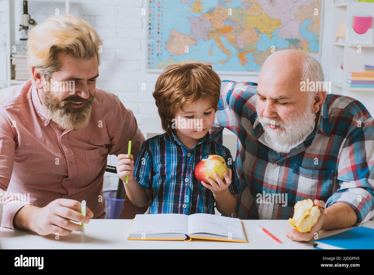 Grandfather father and son learning to write and read. Grandpa teaching ...